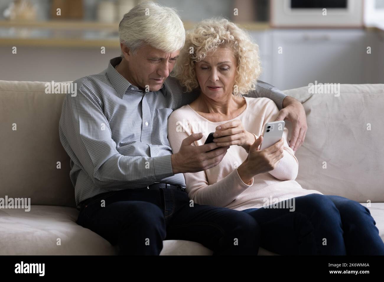 Elderly using two new bought modern smart phones at home Stock Photo ...