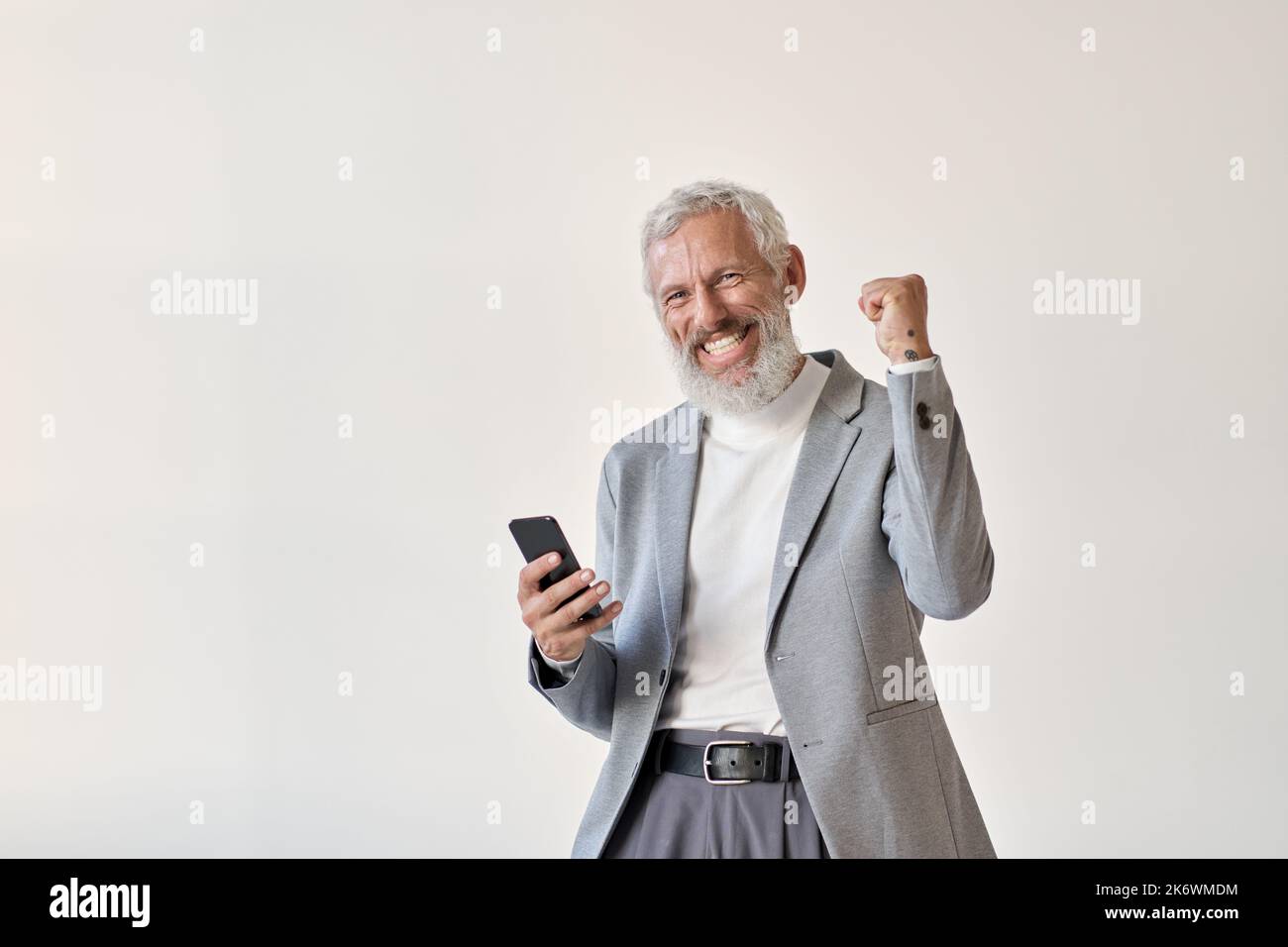 Excited senior old business man investor raising fist using smartphone ...