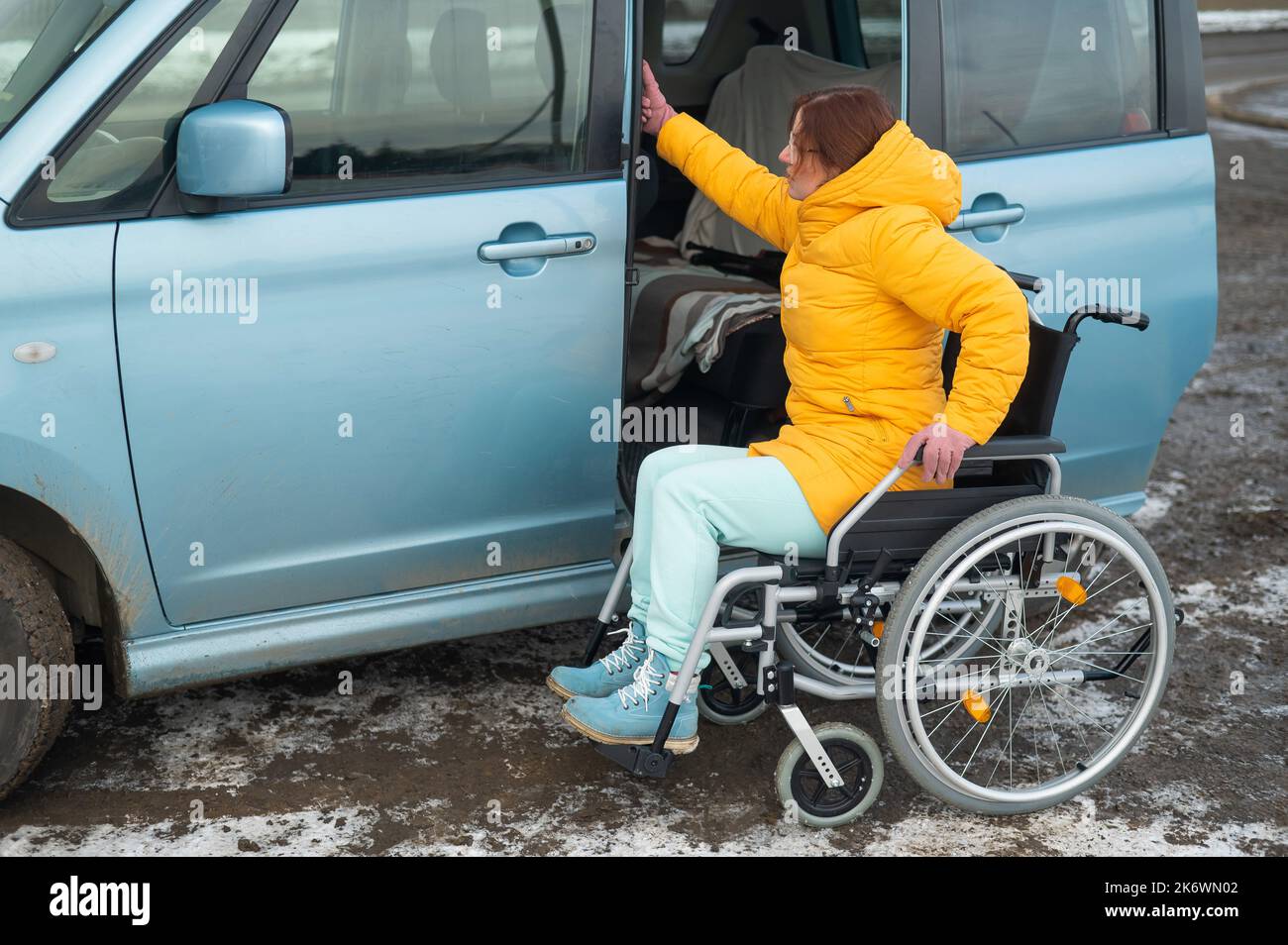 Caucasian woman in a wheelchair gets into the car Stock Photo - Alamy