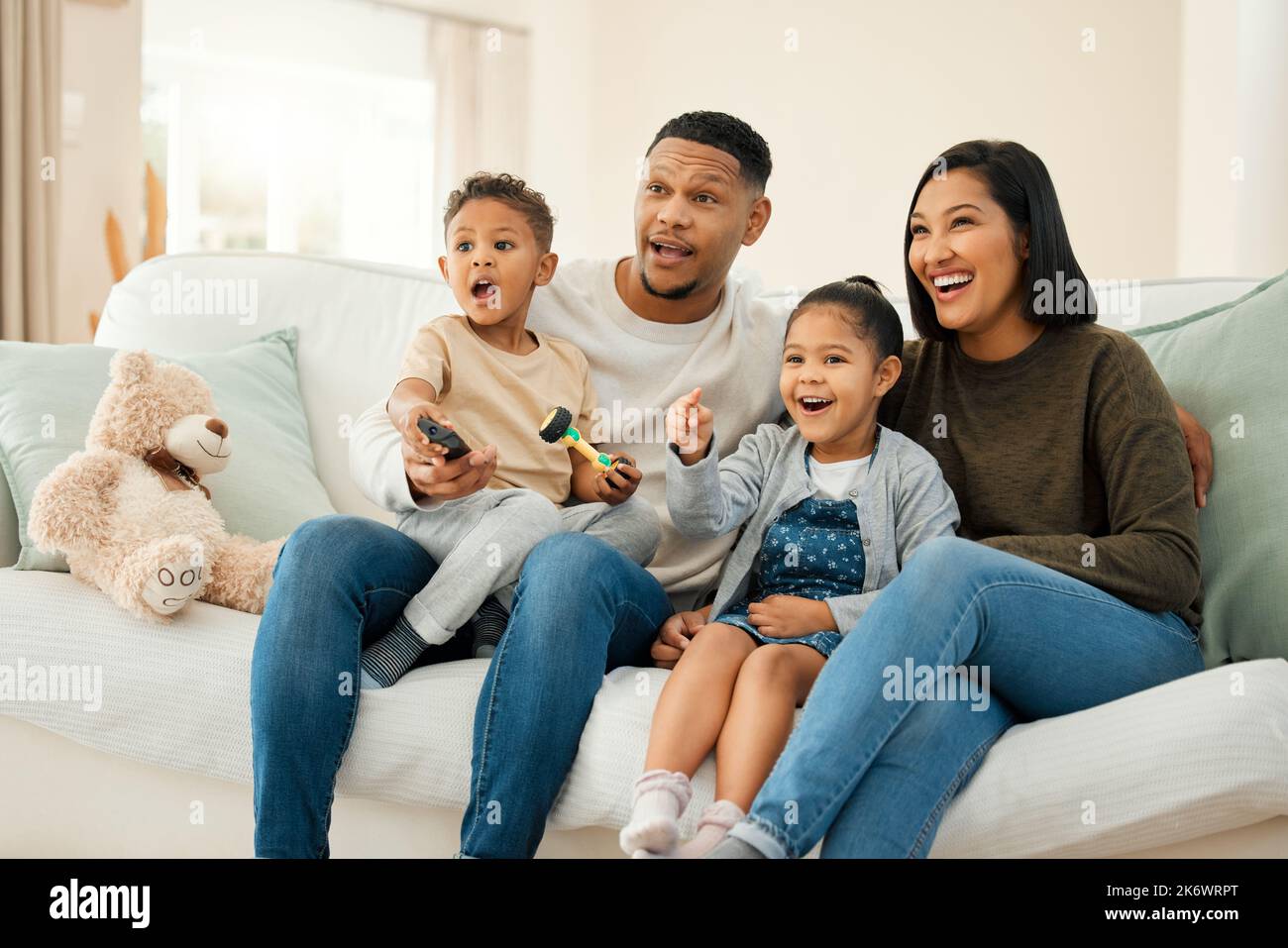 Our family time is always fun. a young family watching tv together at ...