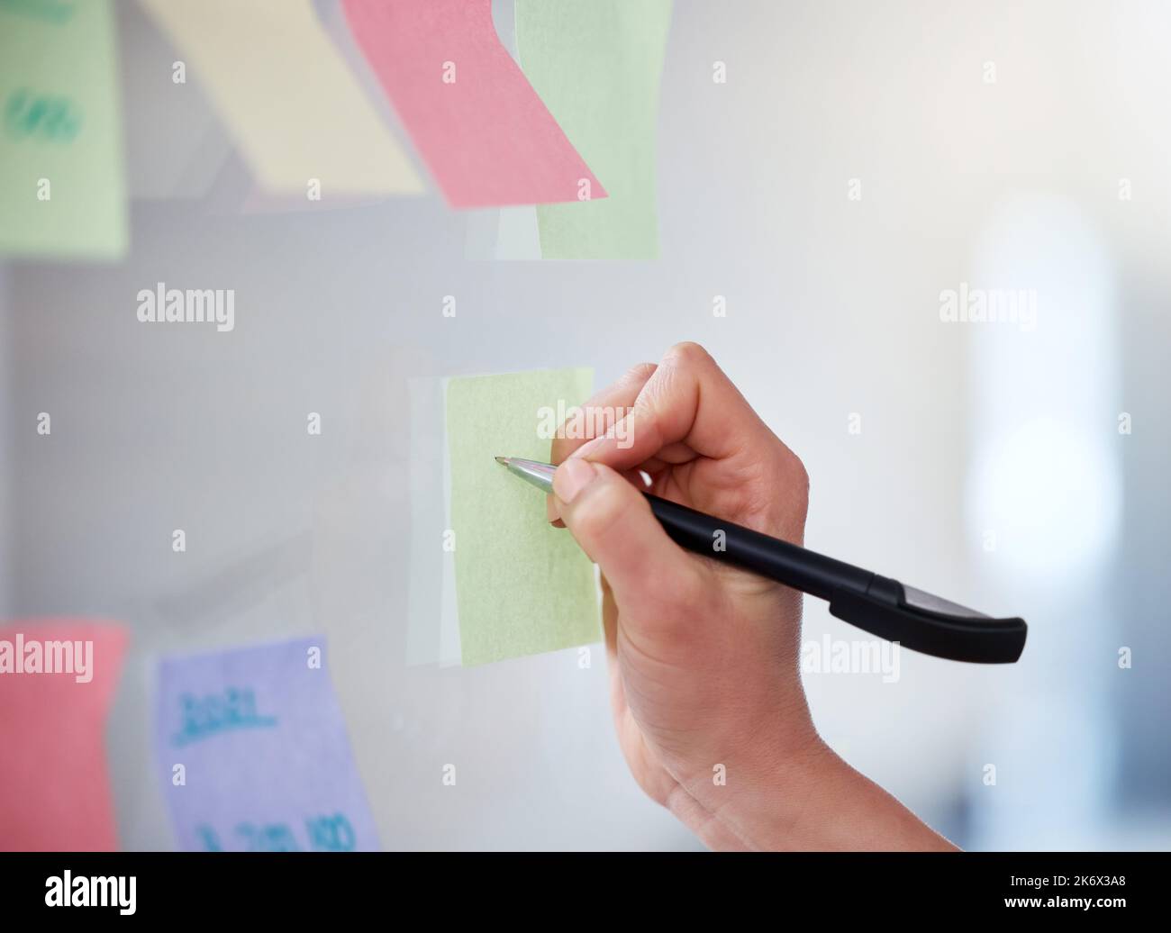 Closeup of unknown business woman writing on sticky notes on a ...