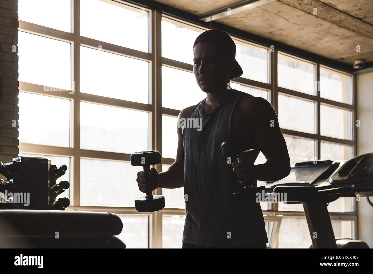 Muscular young male athlete performs exercises with dumbbells. Strength ...