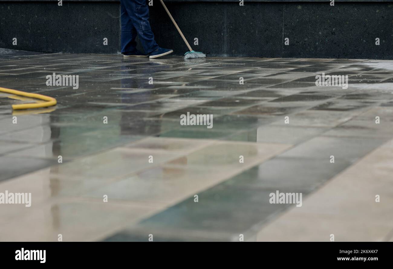 cleaning the floor with mop in street. Regular clean up. Maid cleans ...