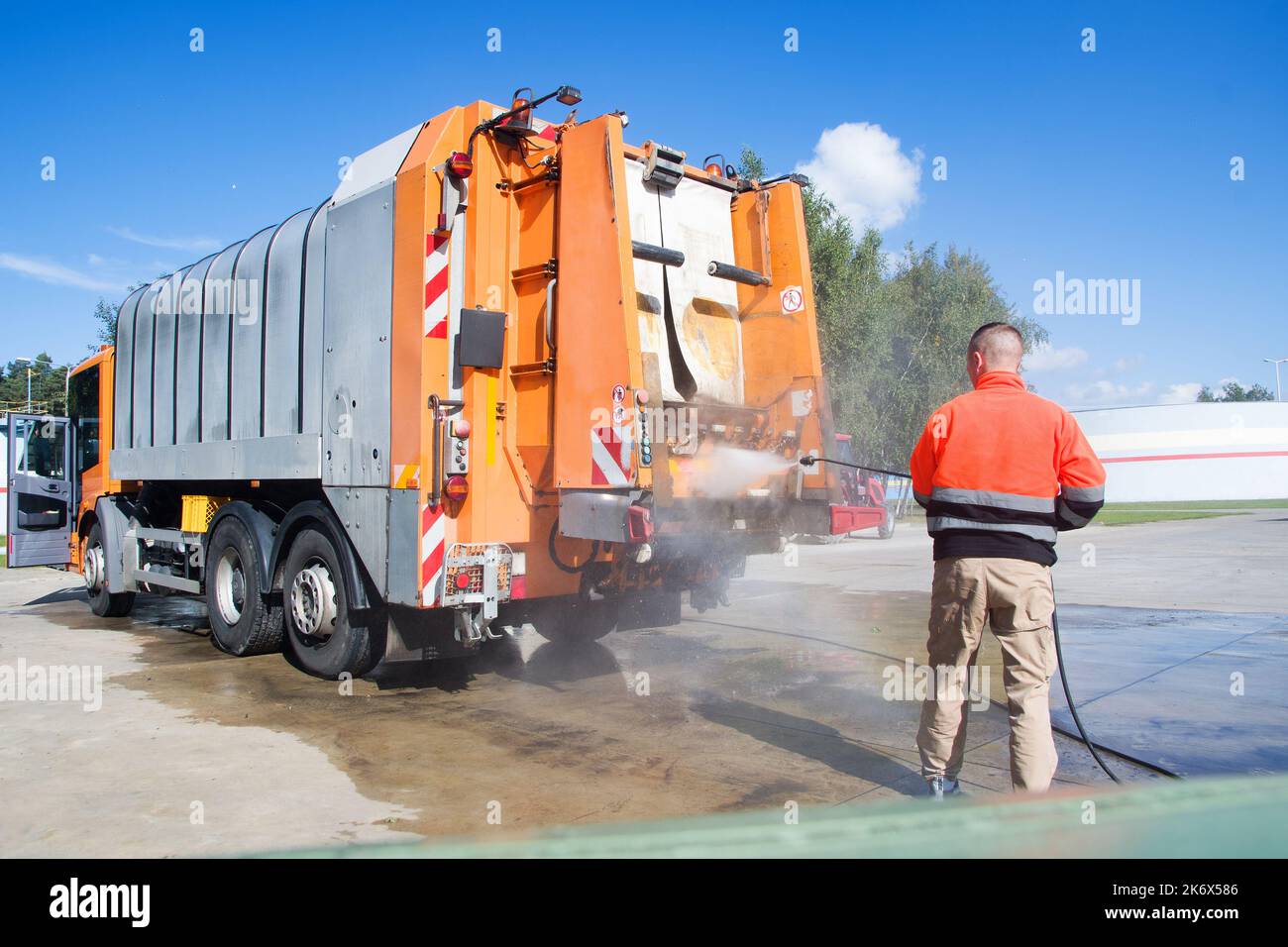 garbage truck Operator Pressure Washing Can After Waste Collection ...
