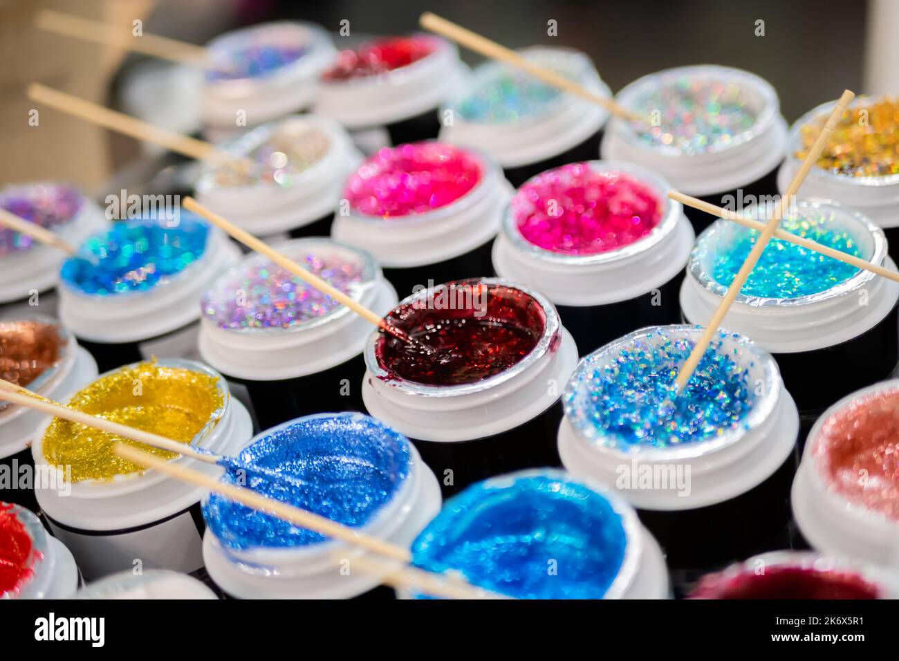 Samples of cosmetic makeup glitter with wooden stick in row: close up ...