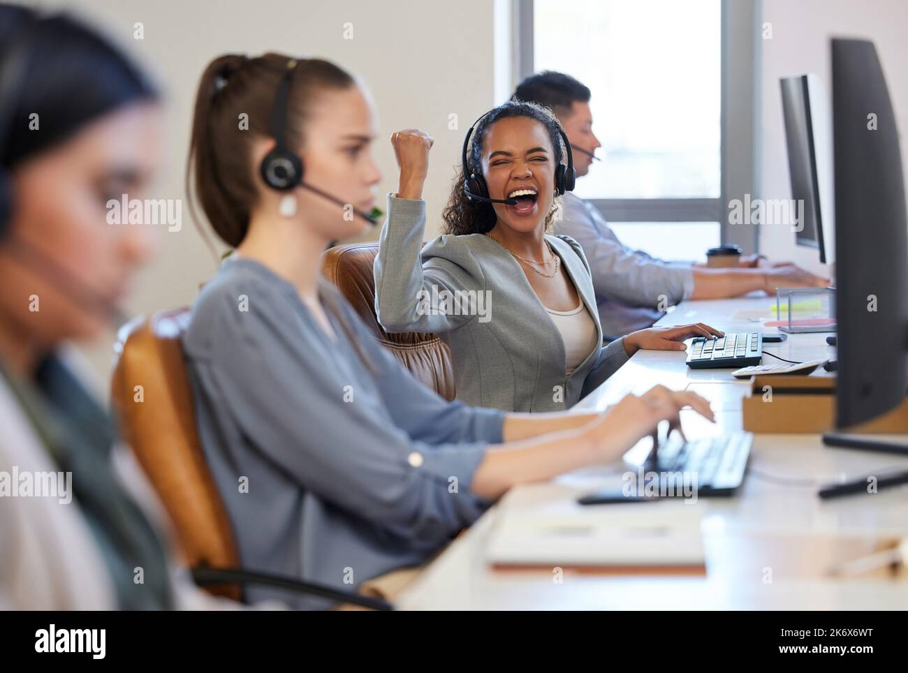 The customer said yes. a young call centre agent cheering while working ...