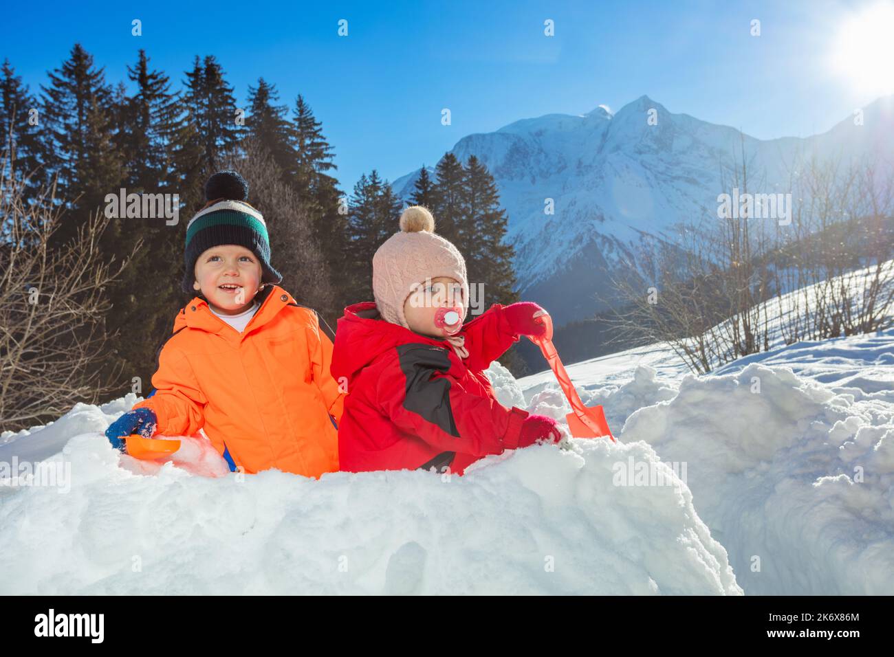 Two kids, boy with sister girl play in snow fortress outside Stock ...