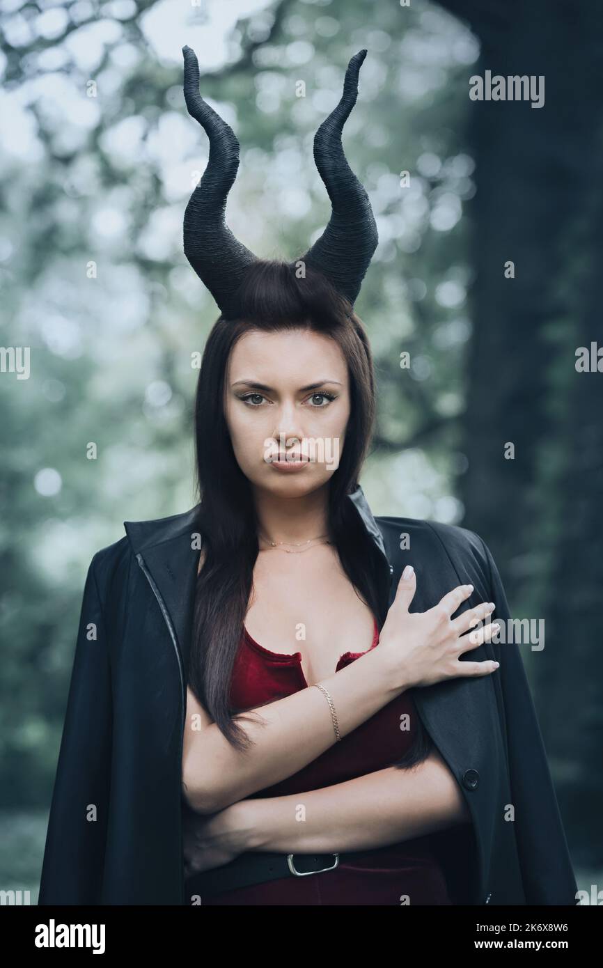 Beautiful woman with long black horns in the forest. Halloween concept ...