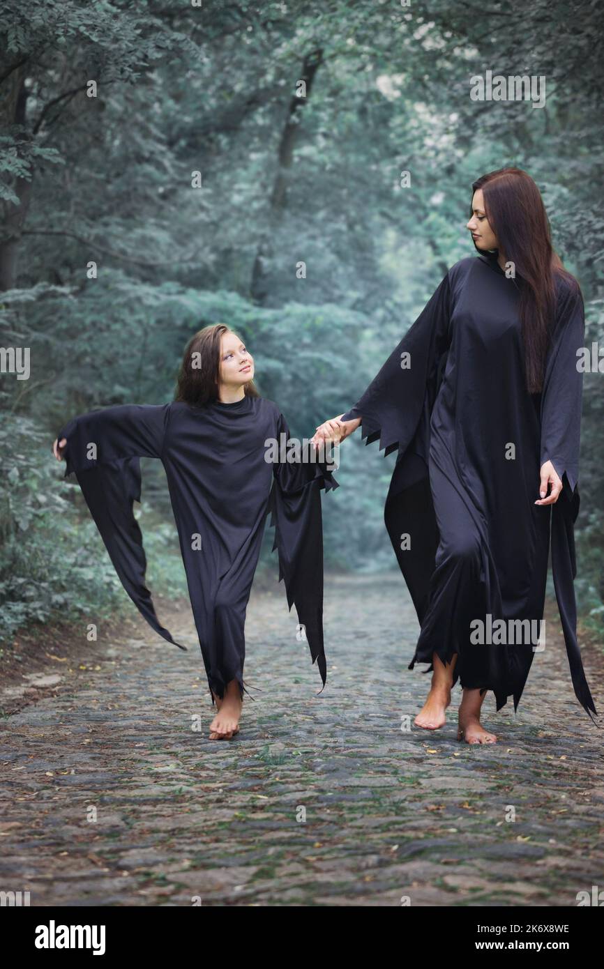An adult witch and her daughter are walking in the forest, Halloween ...