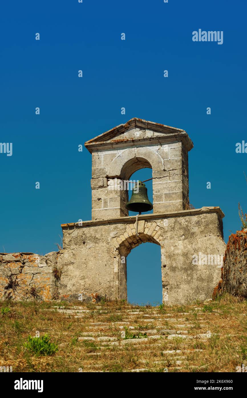 Decayed stone built bell tower with hanging bronze bell on top of a ...