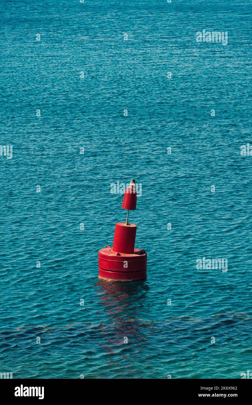 Big red iron navigational buoy with signaling light floating on a blue ...