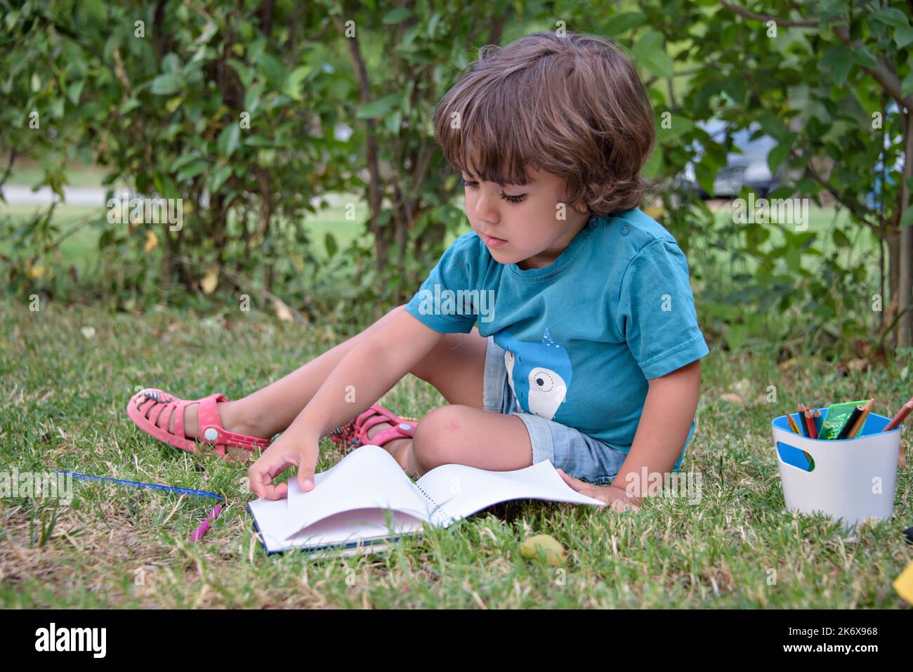 Young Caucasian school boy sitting in park outdoor doing school ...