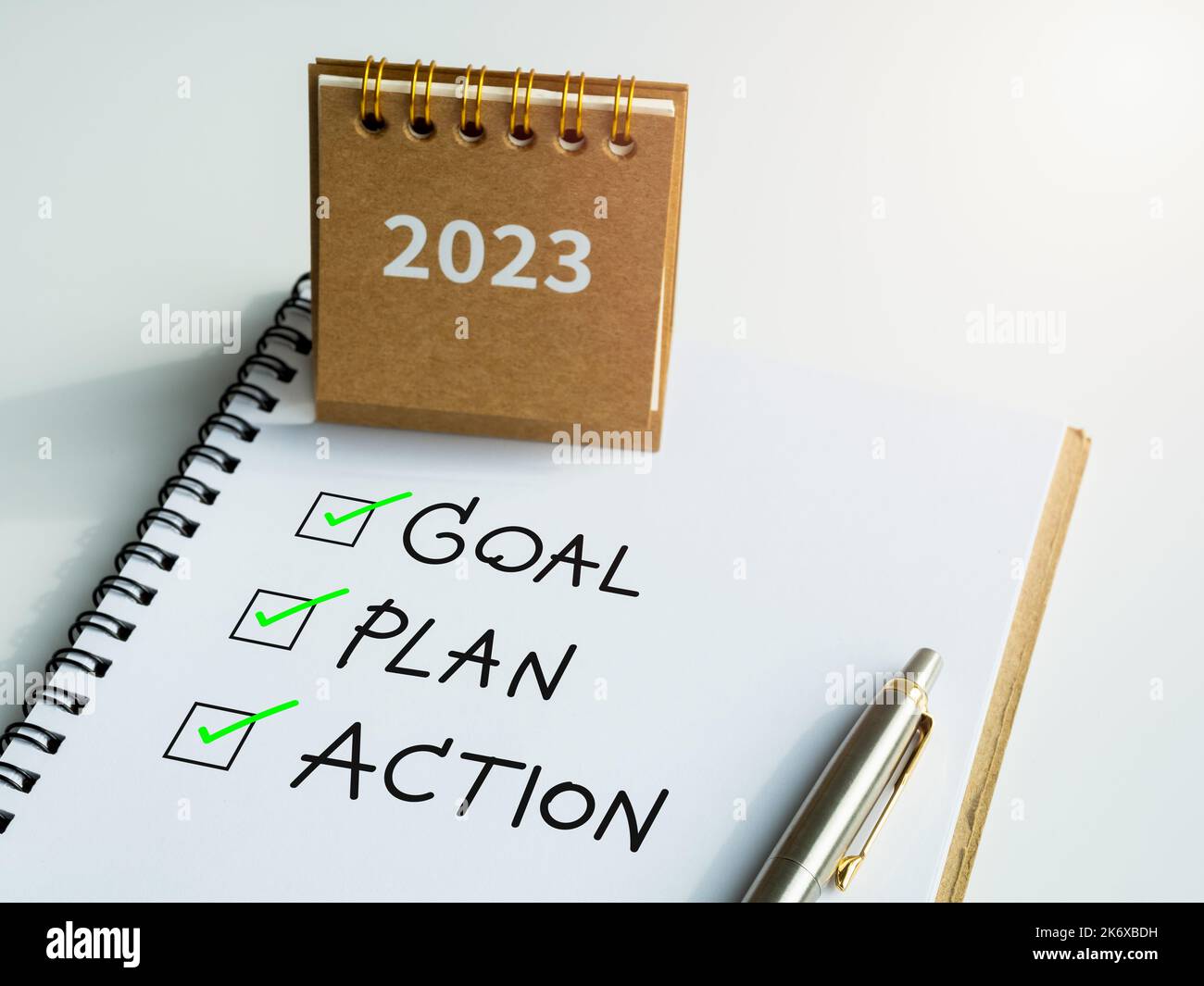 Goal, plan and action, text with checkmarks on notepad with pen and ...