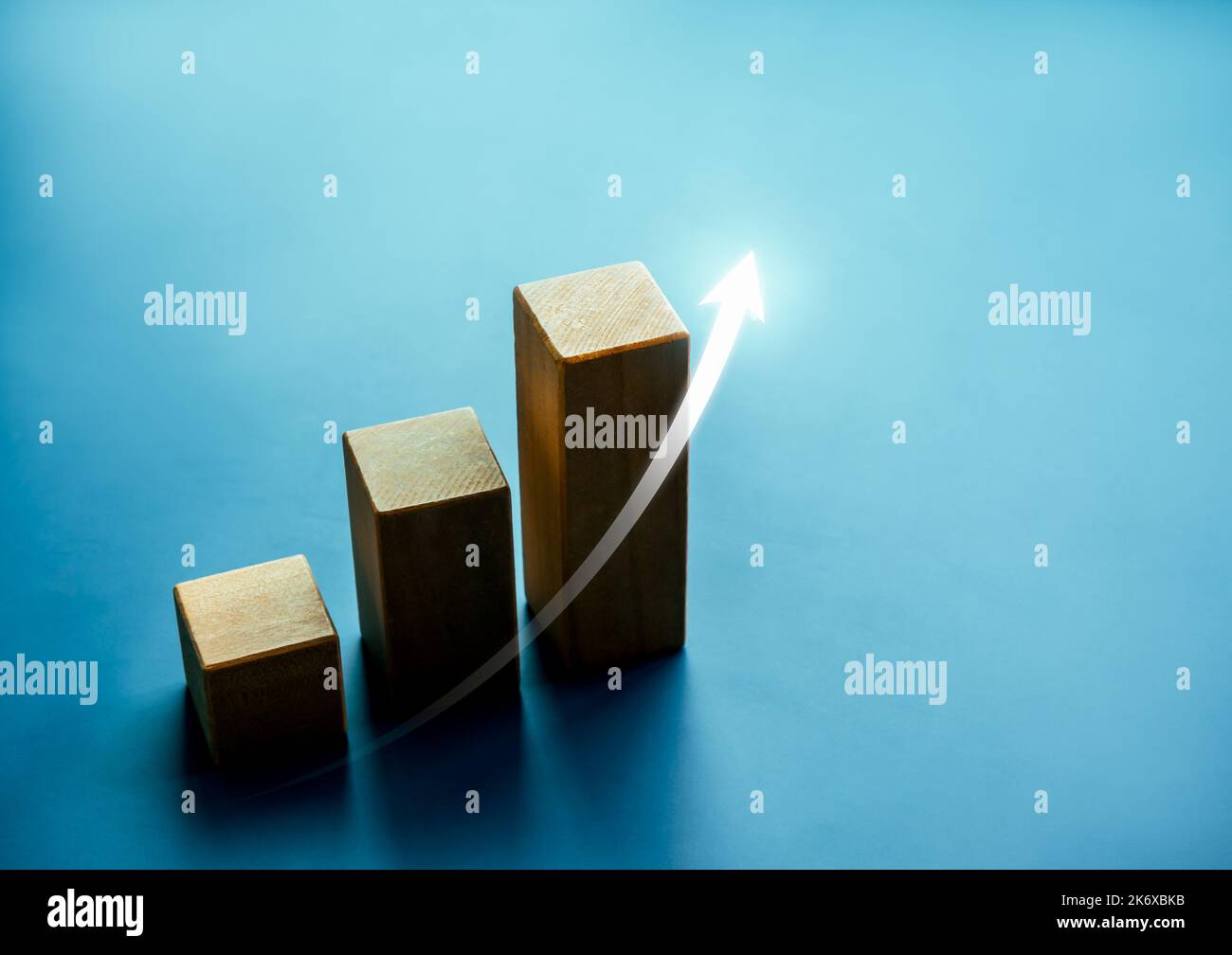 Shining rise up arrow on wooden cube blocks, bar graph chart steps on blue background, business ...