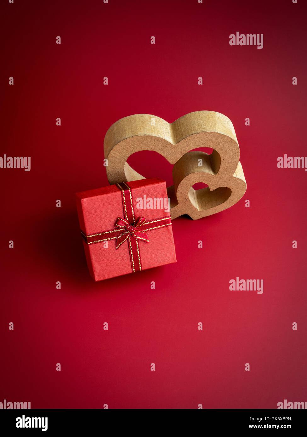 Wooden heart and a small red present gift box with ribbon on red ...