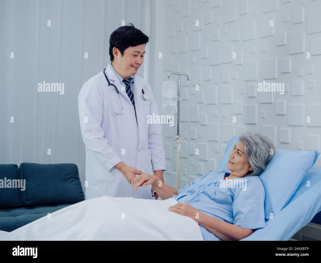 The kind Asian male doctor in white suit visits, talks and gives ...