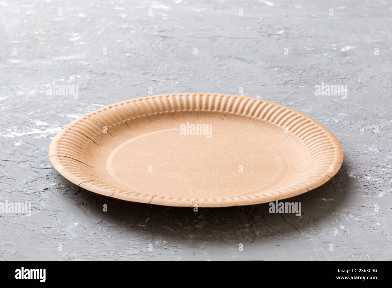 Perspective view of eco paper plate on cement background. Empty space ...