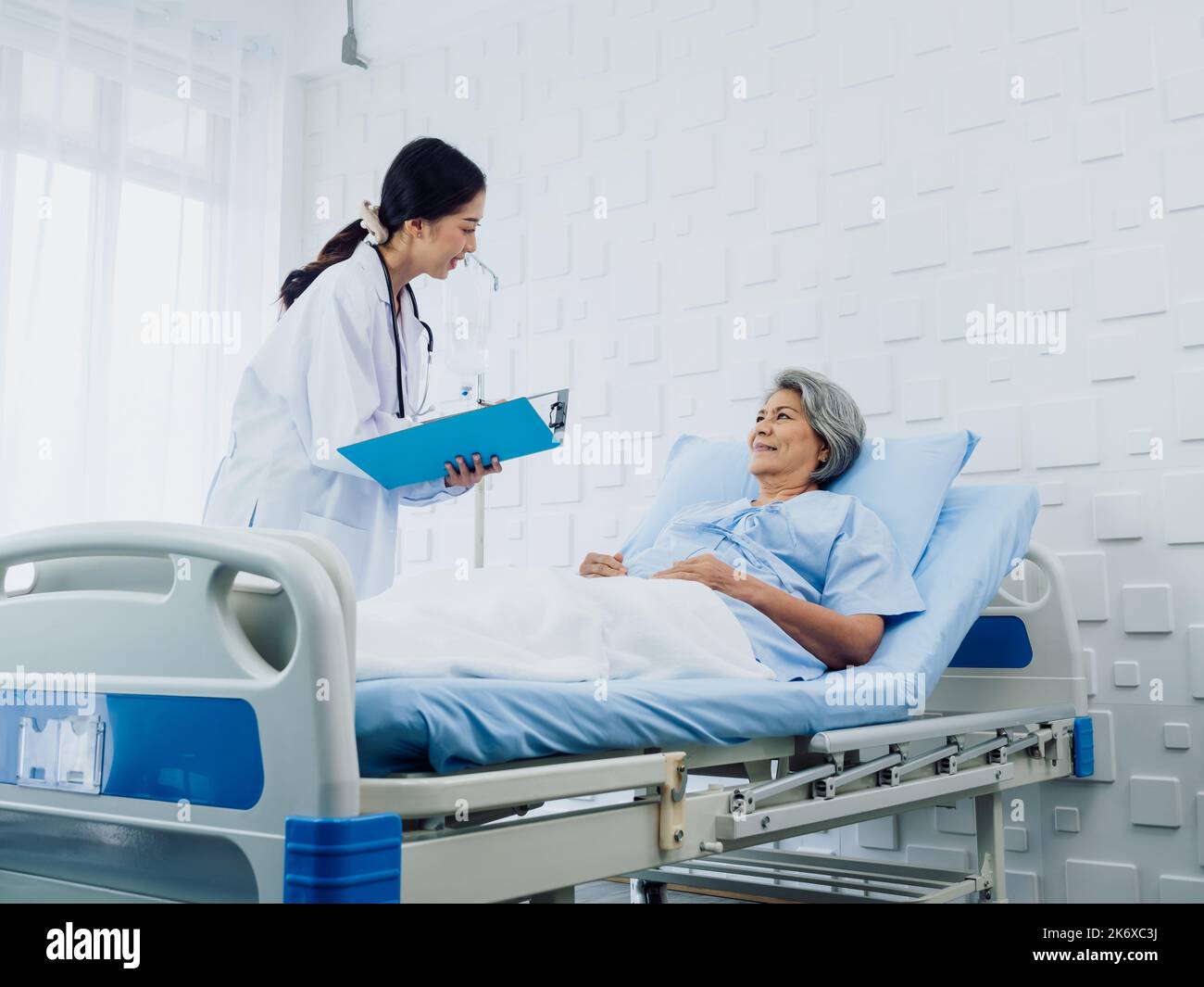 Young Asian female doctors visit senior woman patient in bed ...