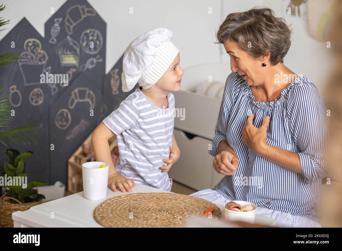 Mother and cute baby boy cooking food at childish kitchen playing chef ...