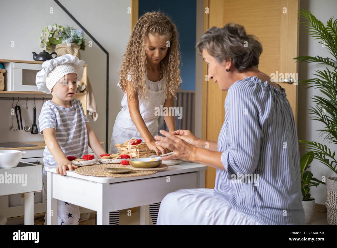 Mother and cute baby boy and girl cooking food at childish kitchen ...