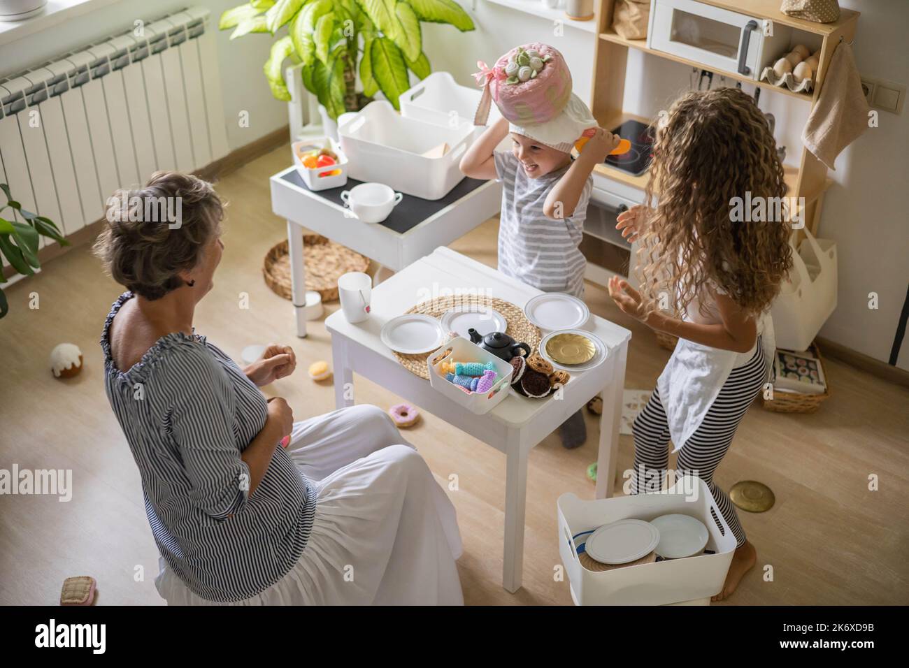 Mother and cute baby boy and girl cooking food at childish kitchen ...