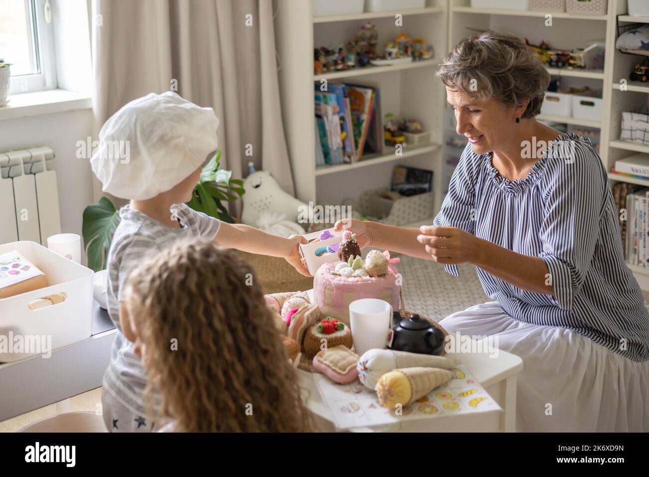 Mother and cute baby boy and girl cooking food at childish kitchen ...