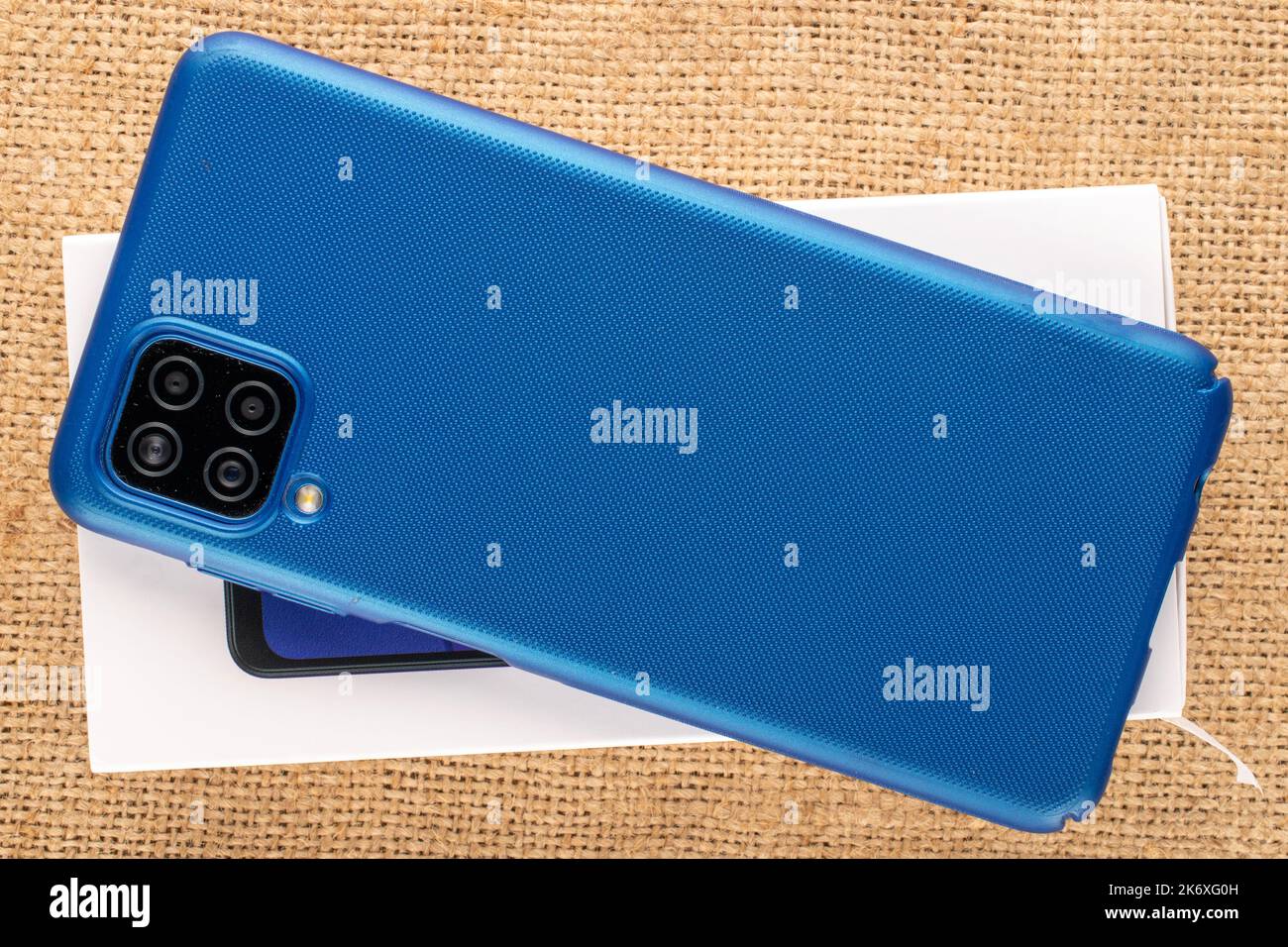 One smartphone with paper packaging on jute cloth, macro, top view ...