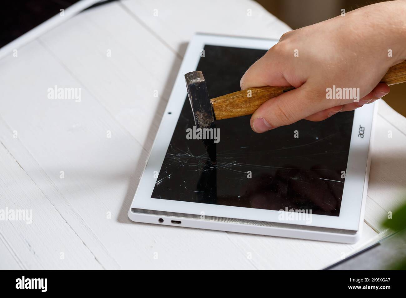 The hammer hits the broken touchscreen tablet, suggesting that it is ...