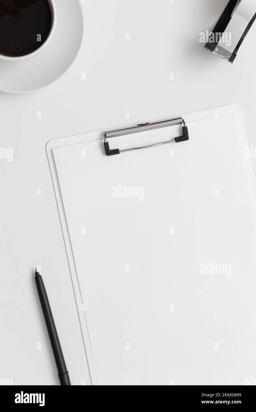 White clipboard mockup with a cup of coffee and workspace accessories ...