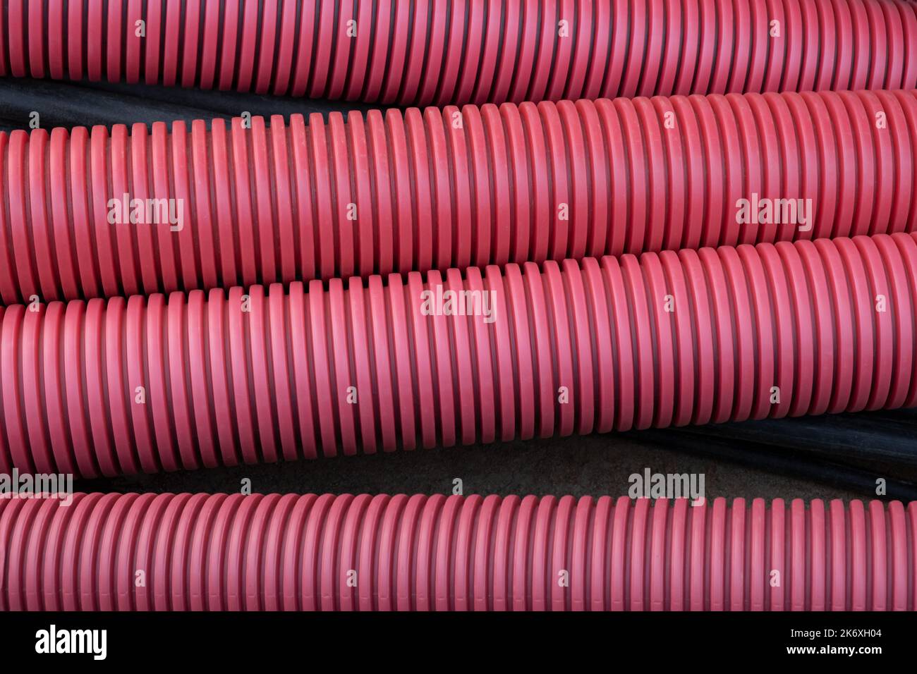 red corrugated pipe are buried underground on the street. underground ...