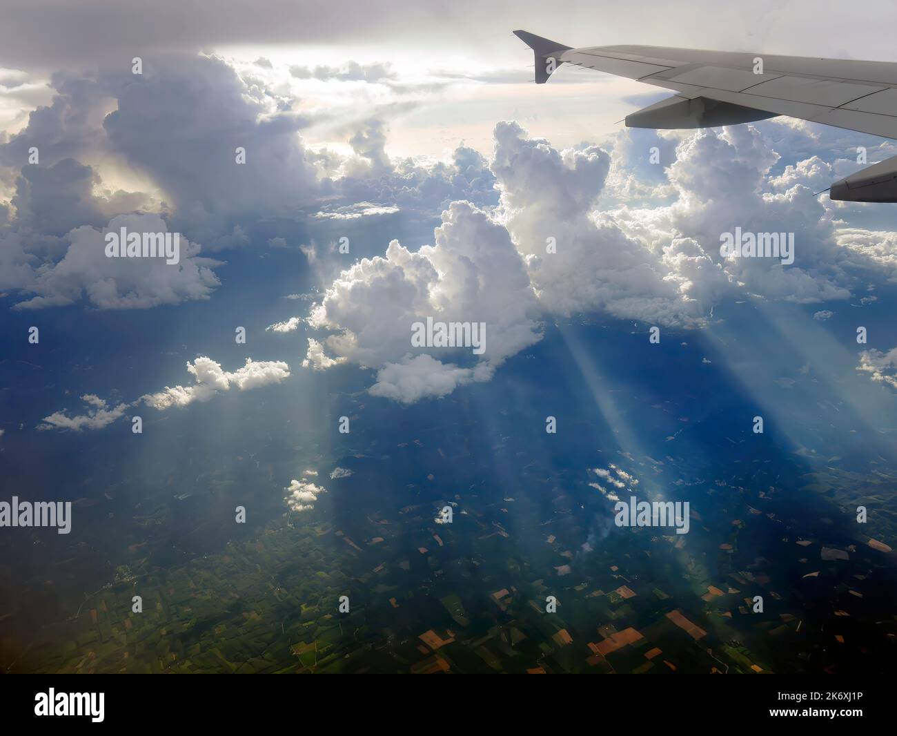 Aerial view flying above dramatic fluffy clouds and sun rays piercing ...