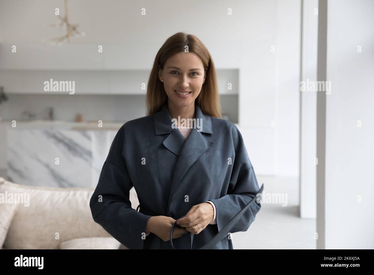 Woman trying on new grey coat smiling staring at camera Stock Photo - Alamy