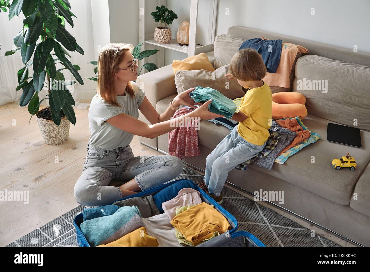Mother and child are packing things in a suitcase together. Family ...