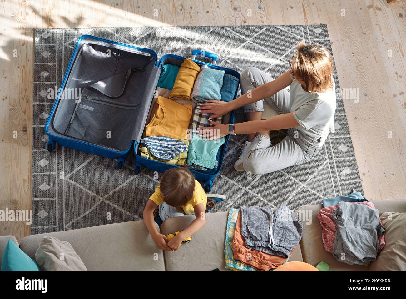 Mother and child are packing things in a suitcase together. Family ...