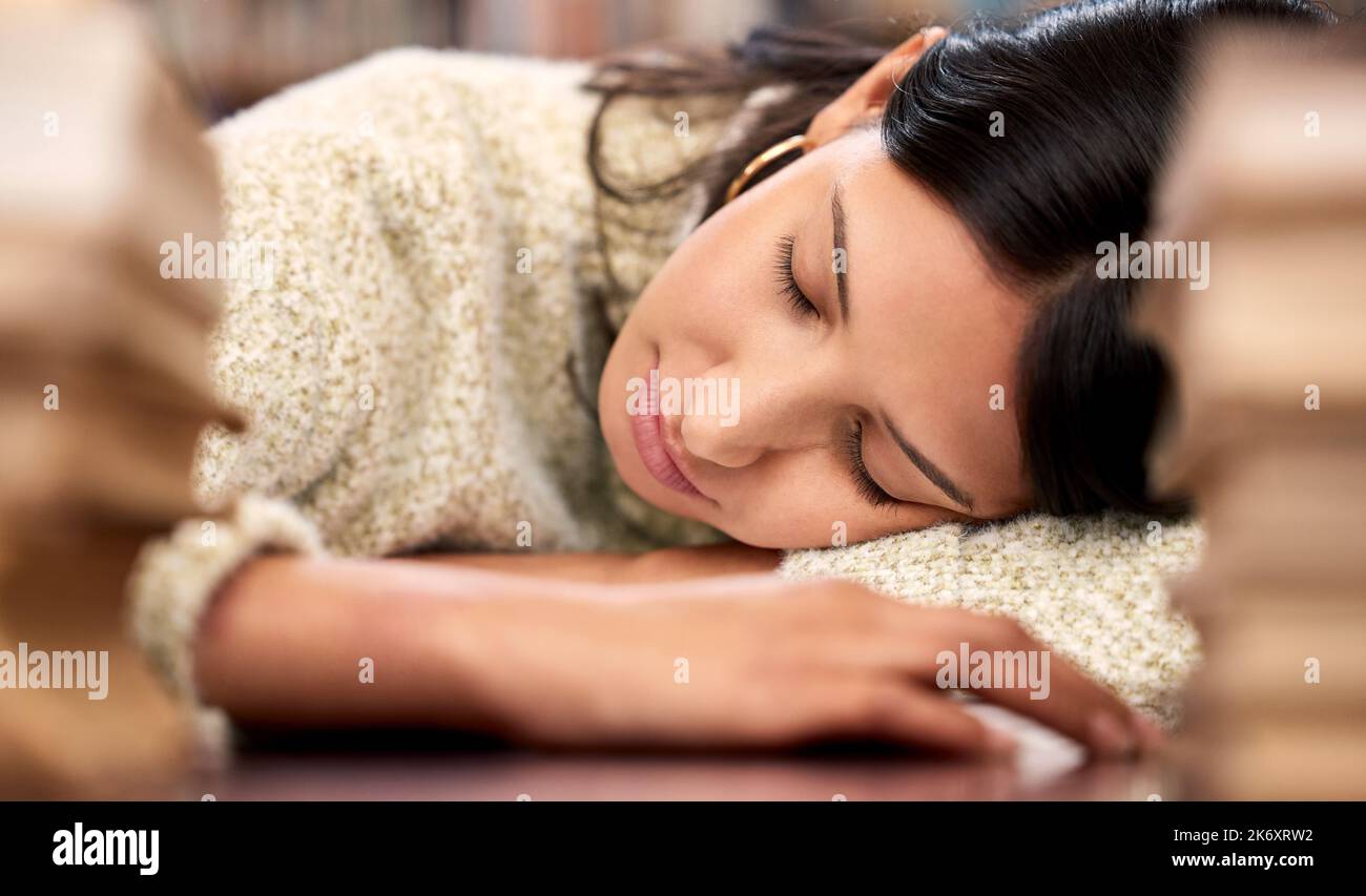 Ill just take a quick nap. a young woman sleeping while studying in a ...