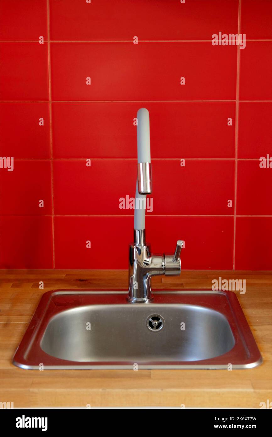 modern steel kitchen sink and tap against bright red tiles Stock Photo ...