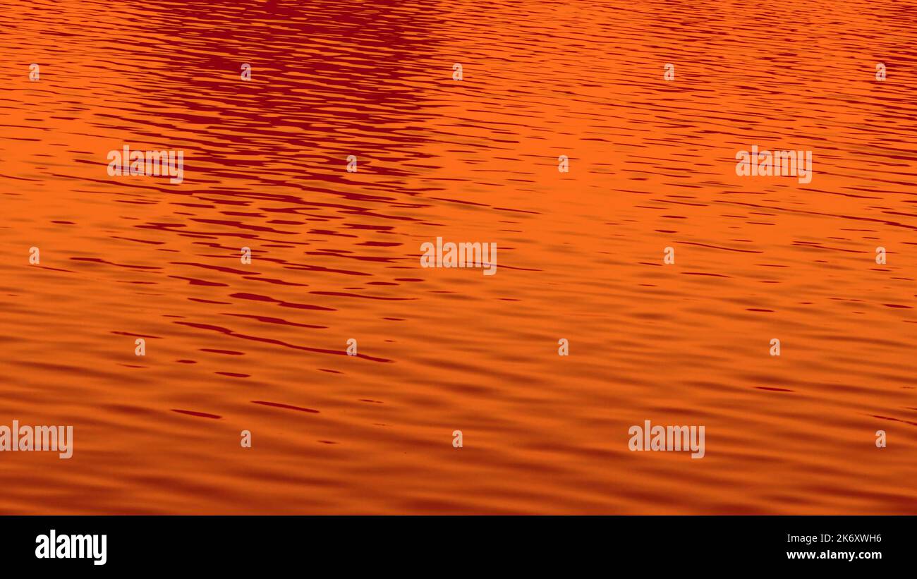 Abstract orange background of water ripples, close-up of the river flow ...