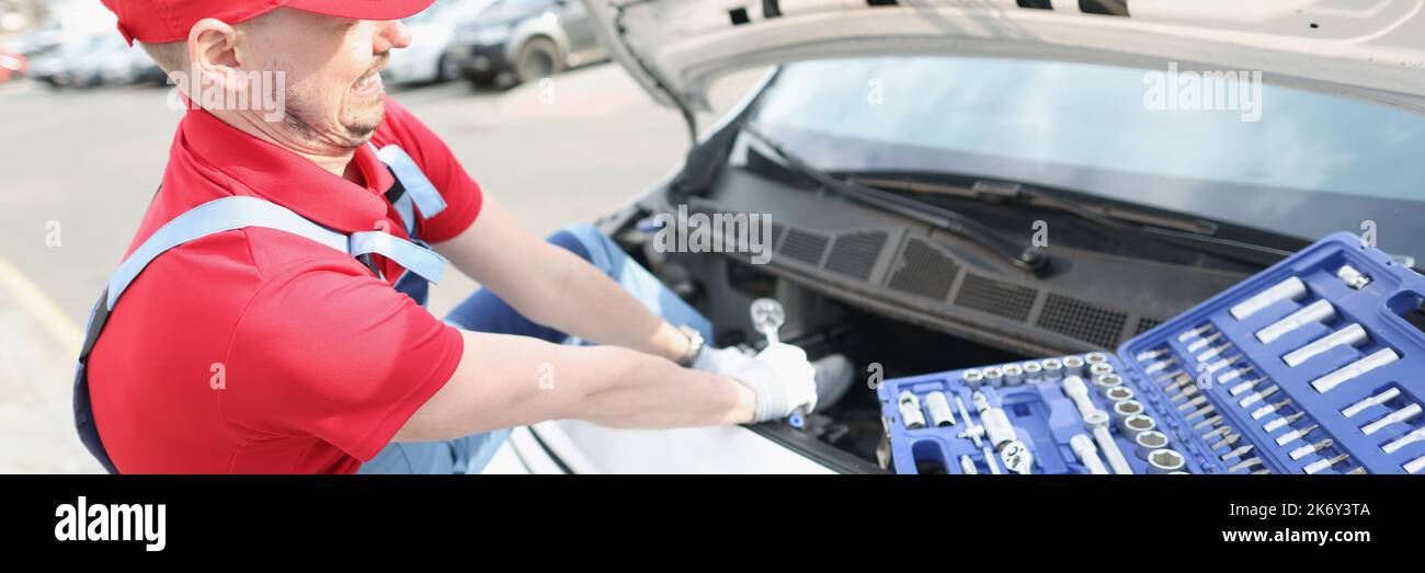 A man on street fixes a breakdown in a car with a wrench Stock Photo ...