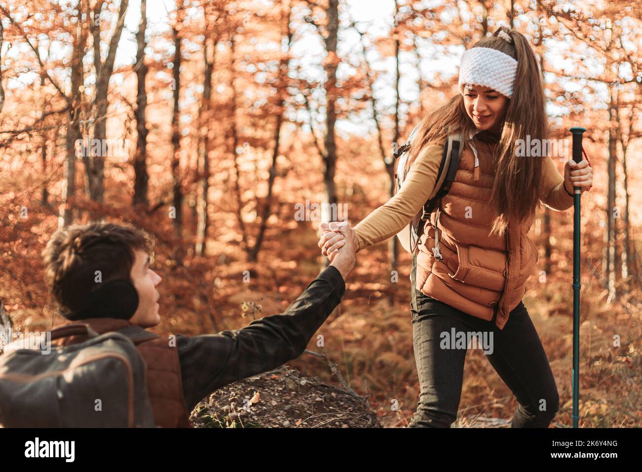 Girl helping her boyfriend to climb over the obstacle while hiking ...