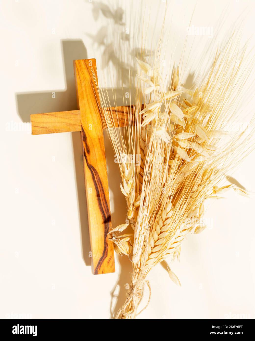 Wooden crucifixion with bouquet of wheat and rye on light background ...