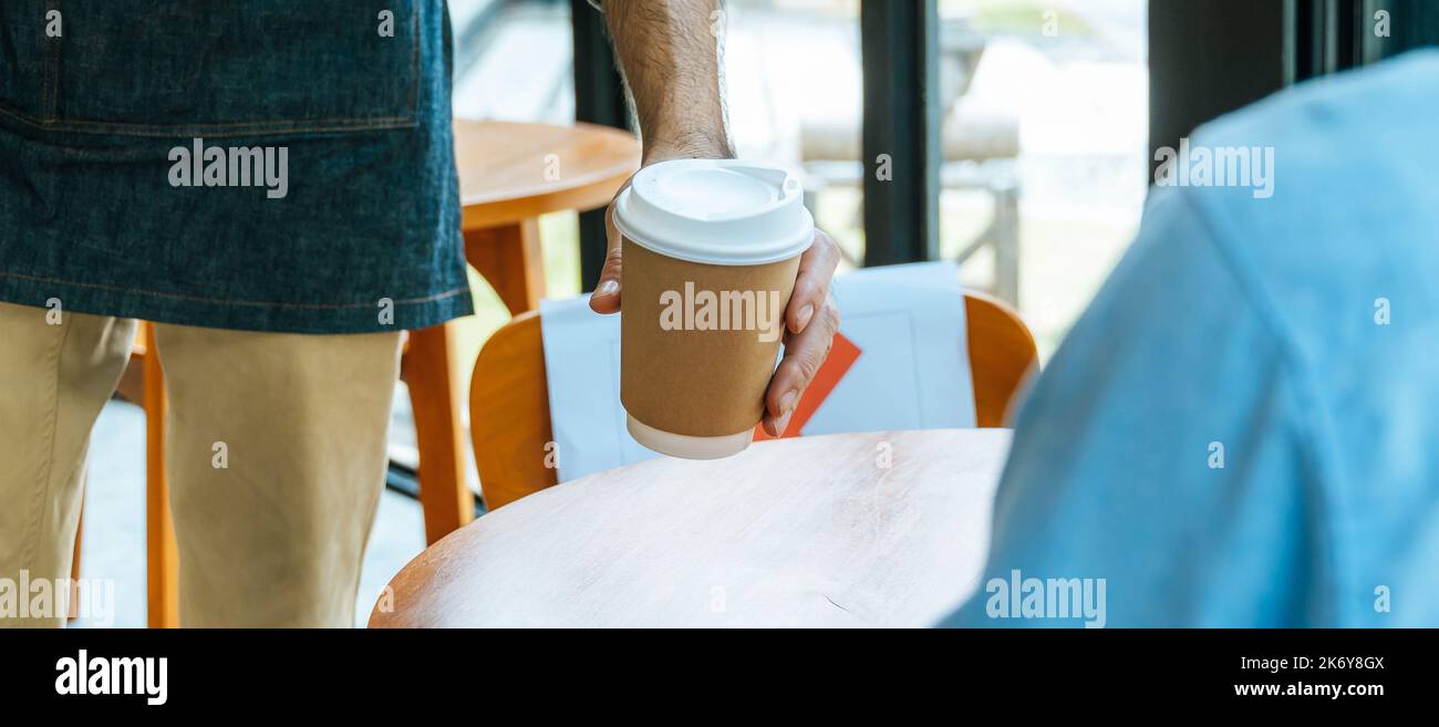 cropped view staff wearing apron serving hot black coffee cup to ...