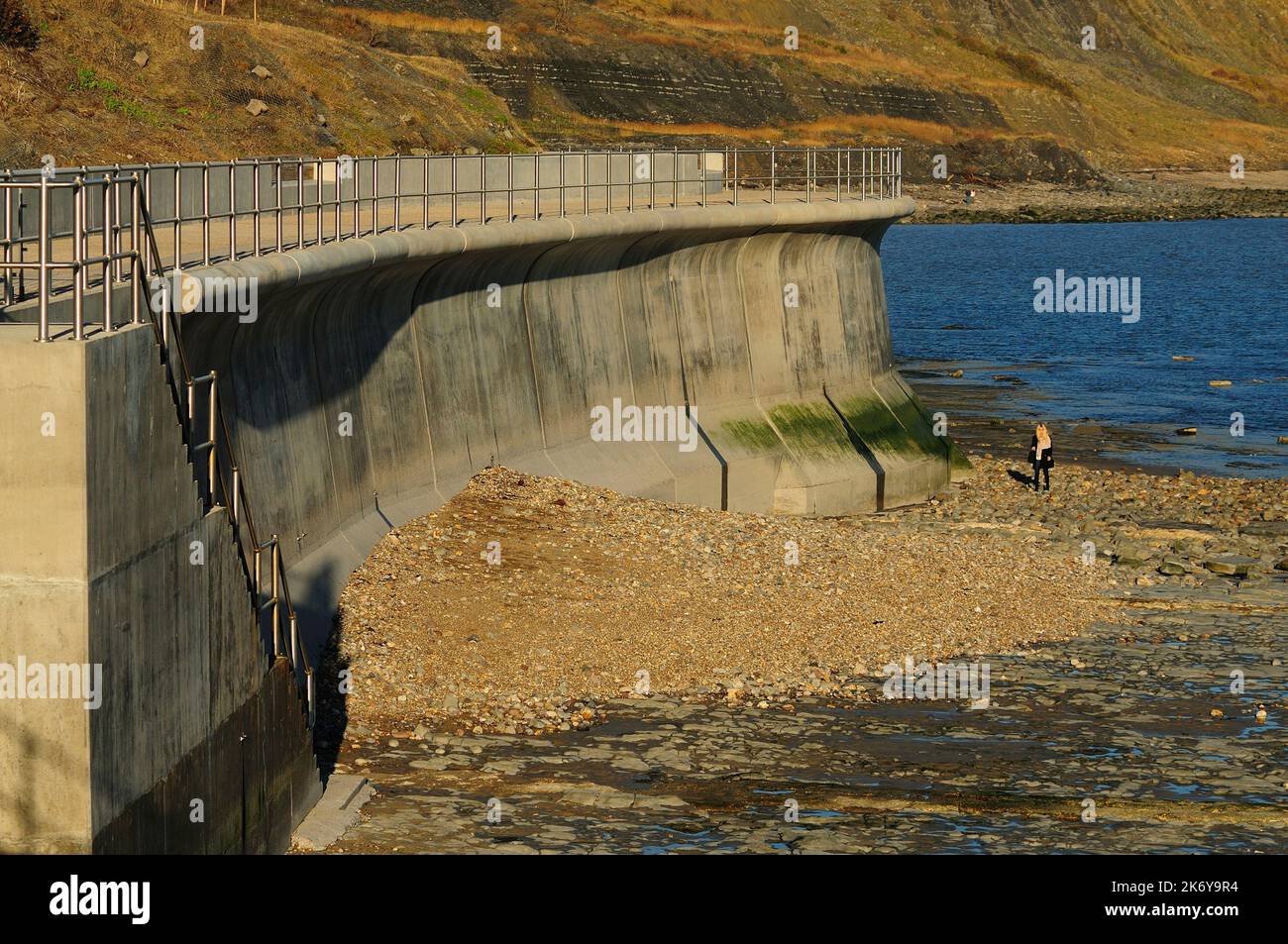 Lady walking on beach under Lyme Bay sea defence Stock Photo - Alamy