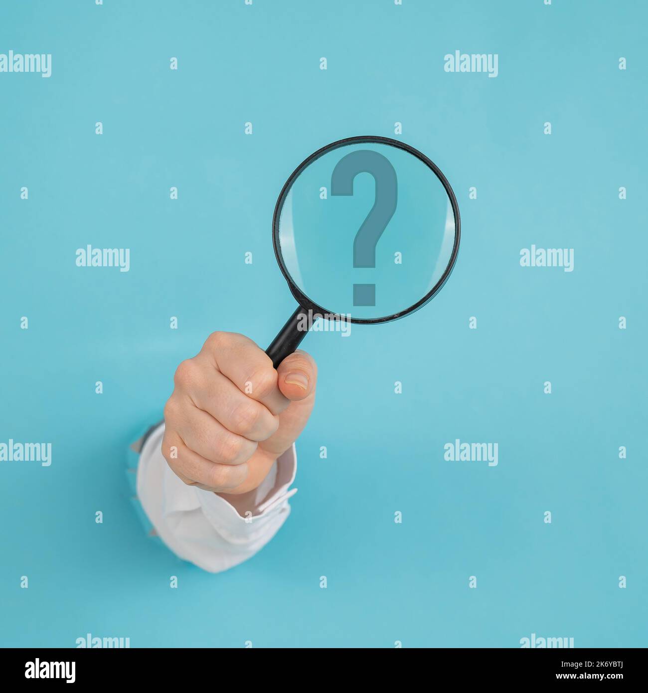 A woman's hand sticking out of a hole on a blue paper background holds ...