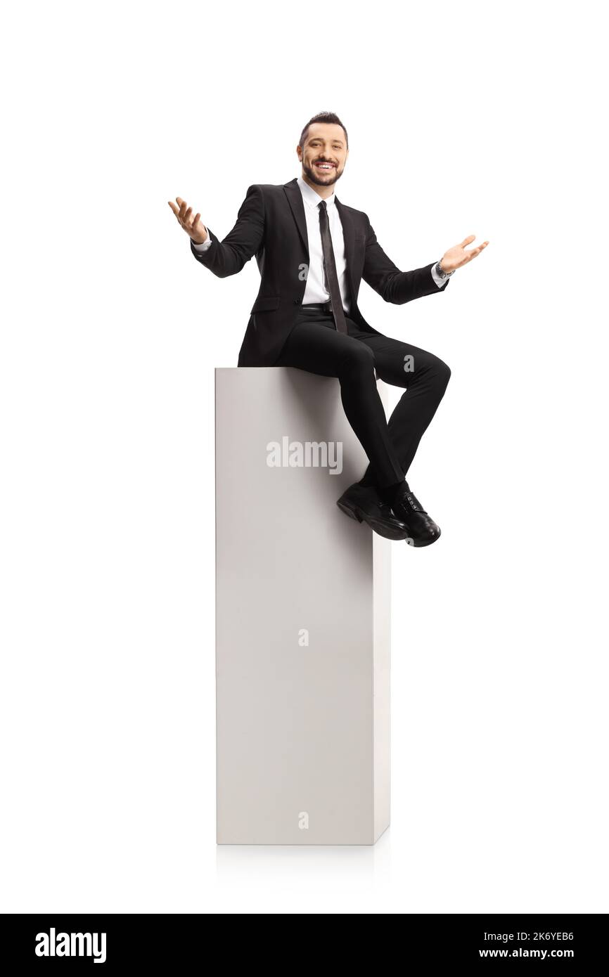 Cheerful businessman sitting on a tall white column and smiling at ...