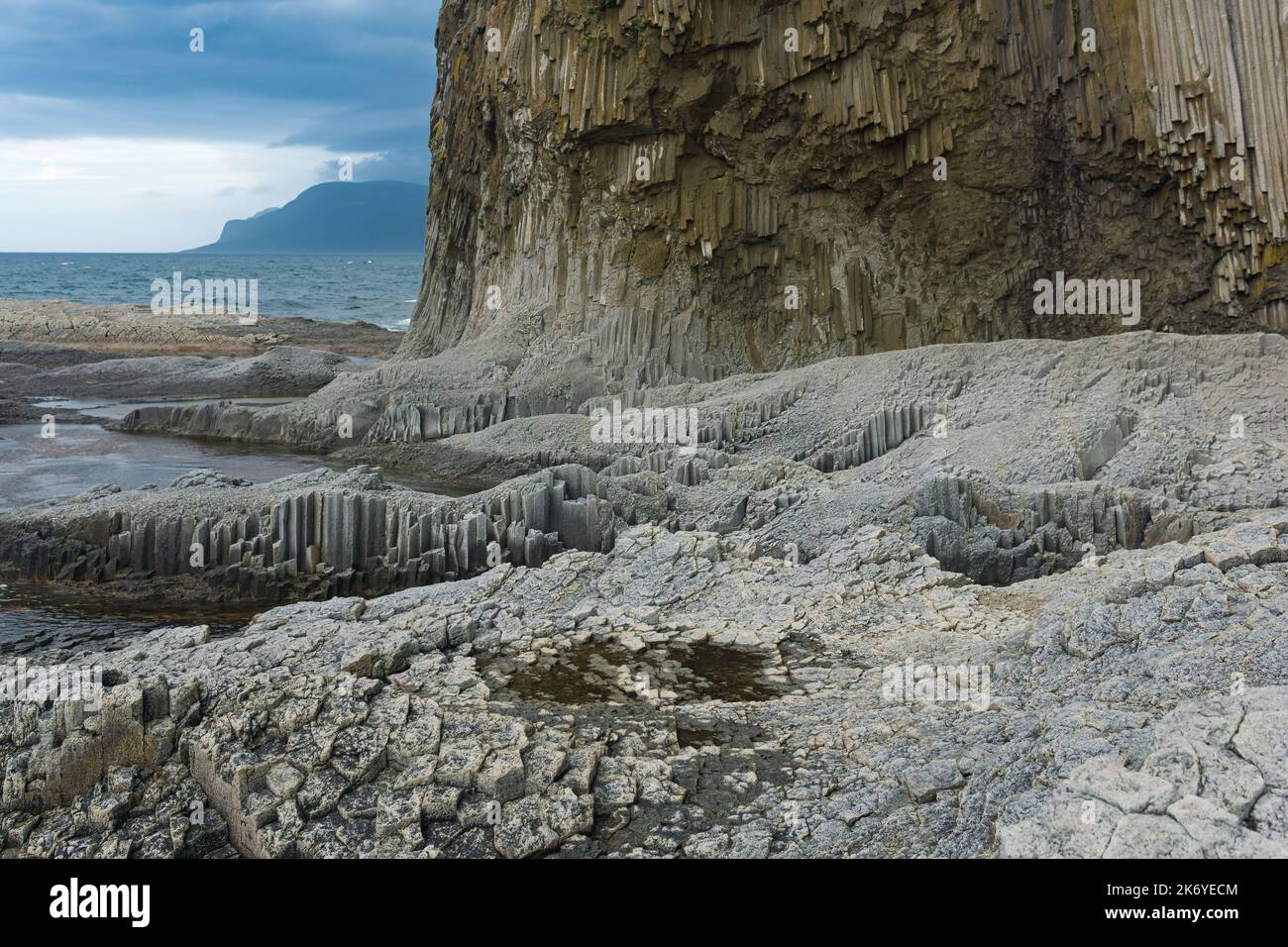 rocky seashore formed by columnar basalt against the backdrop of a ...