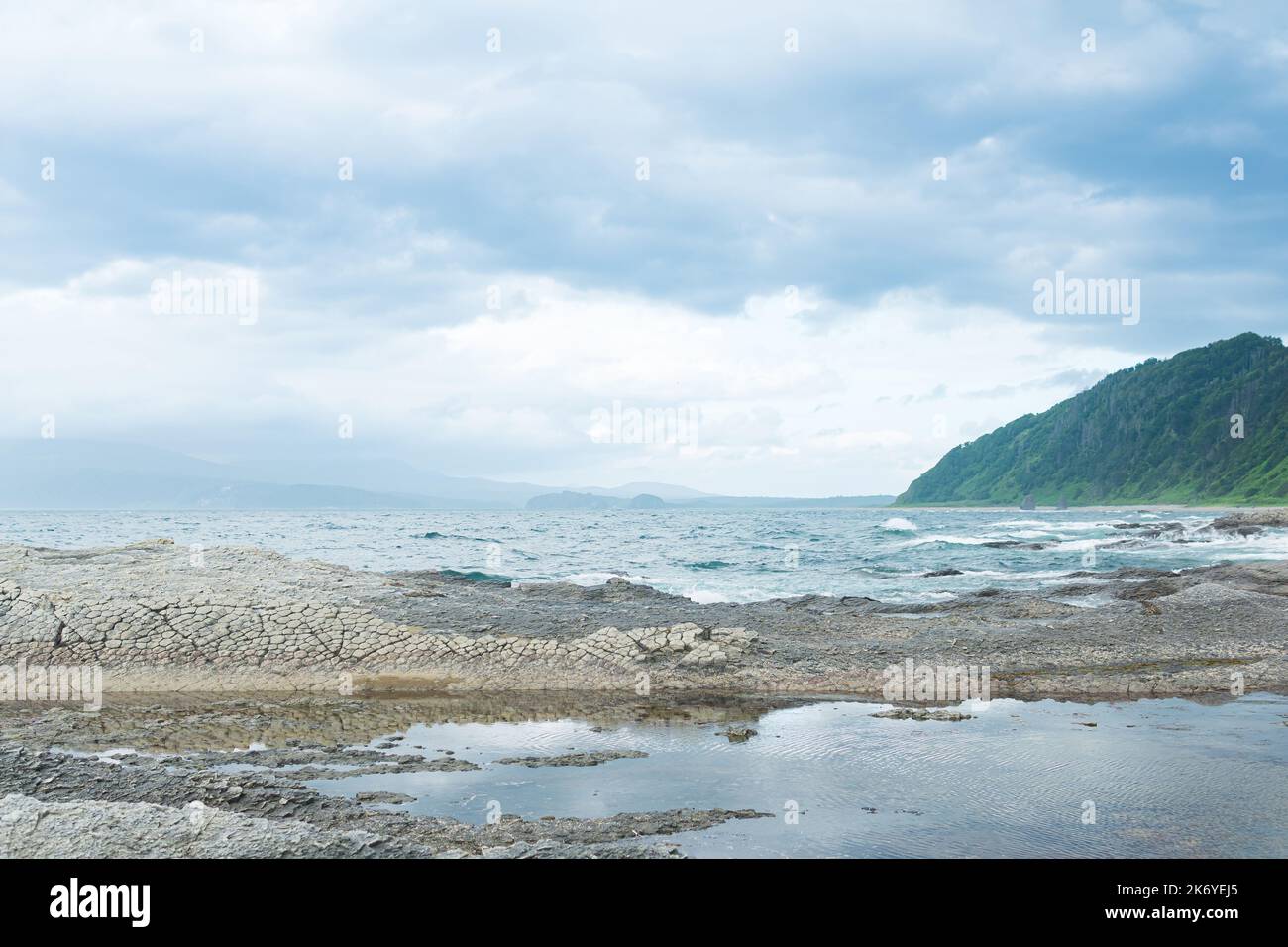 coastal landscape with beautiful columnar basalt cliff on the wooded ...
