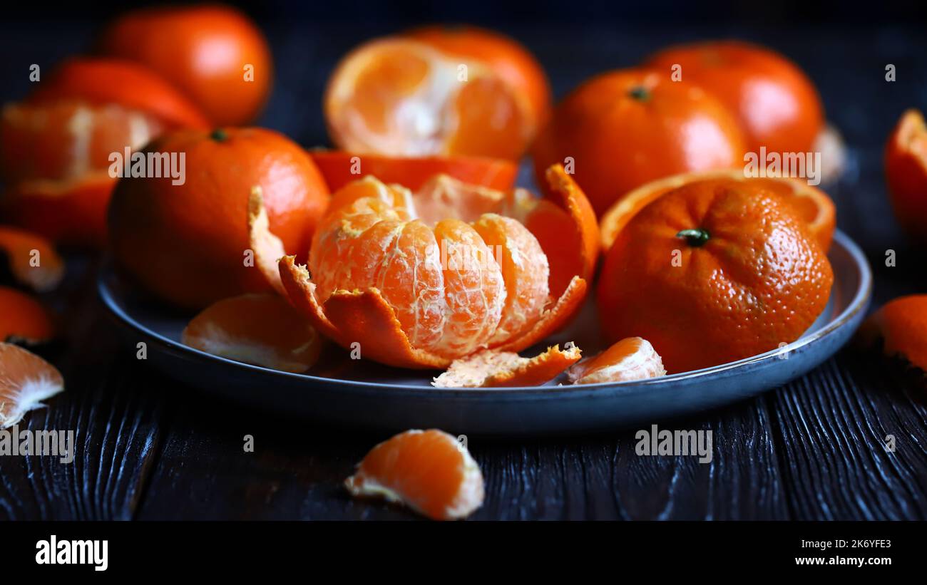 Juicy ripe tangerines on a plate. Peeling a tangerine. Skins of citrus ...