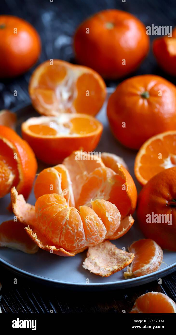 Juicy ripe tangerines on a plate. Peeling a tangerine. Skins of citrus ...
