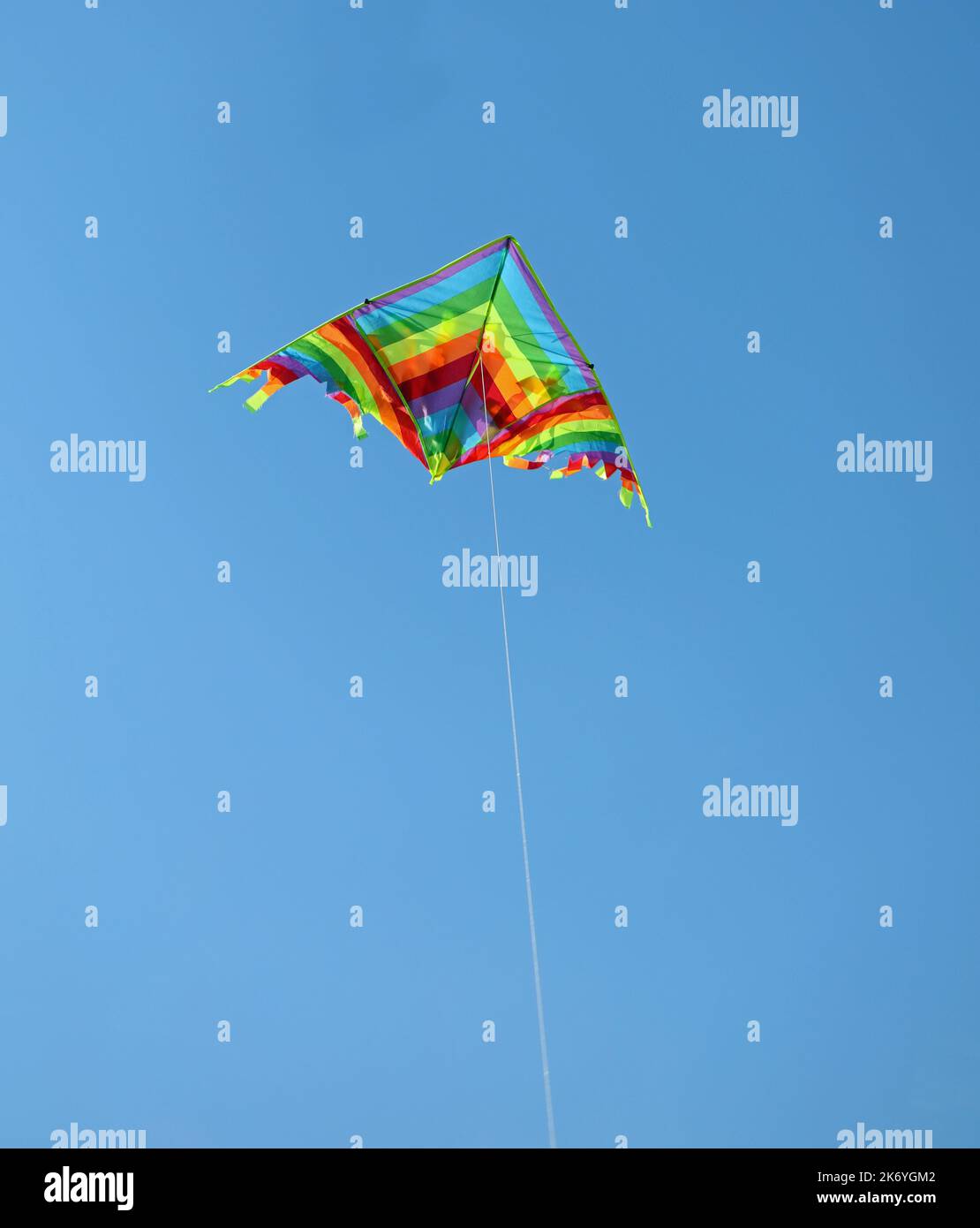 colorful kite flies high in the blue sky tied to a string Stock Photo ...