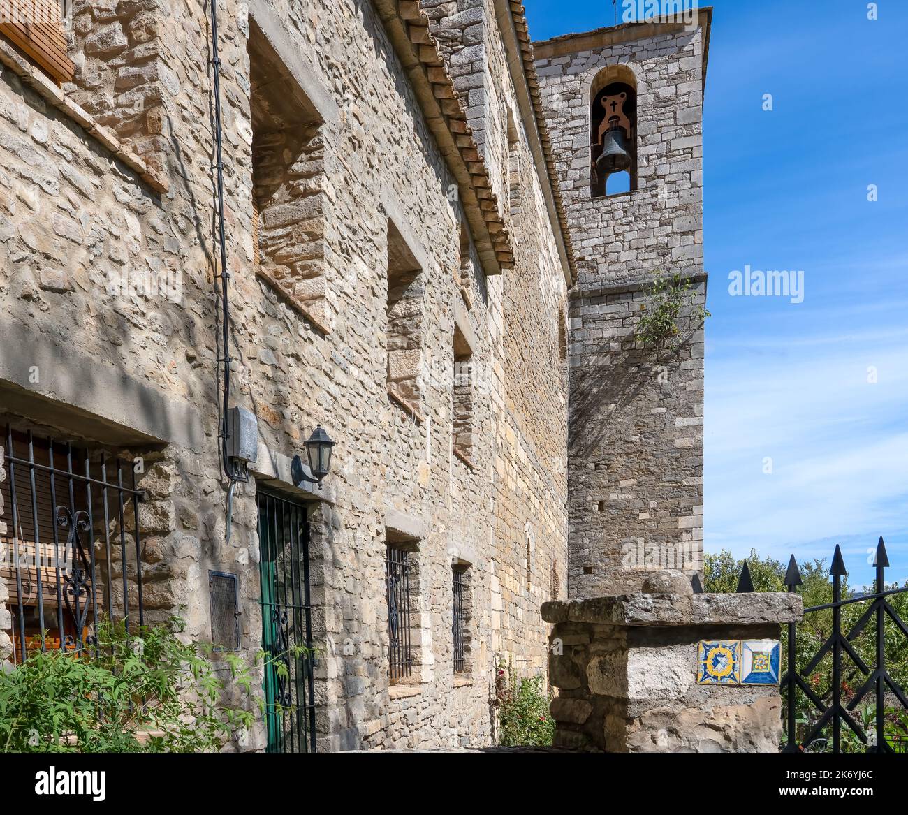 typical Spanish pyrenees dwelling built of local stone, church tower ...